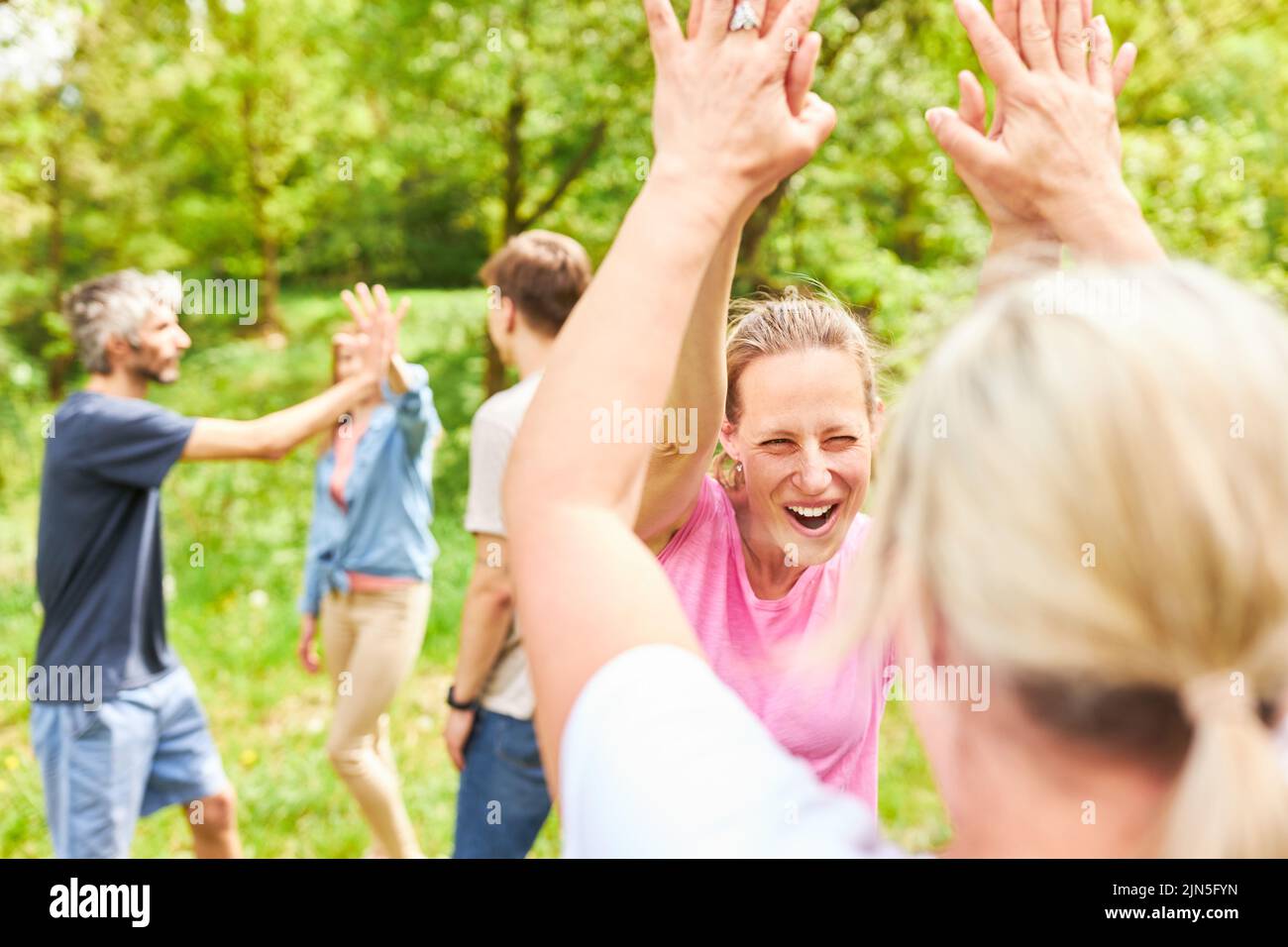 Young people in team building workshop in nature giving high five for ...