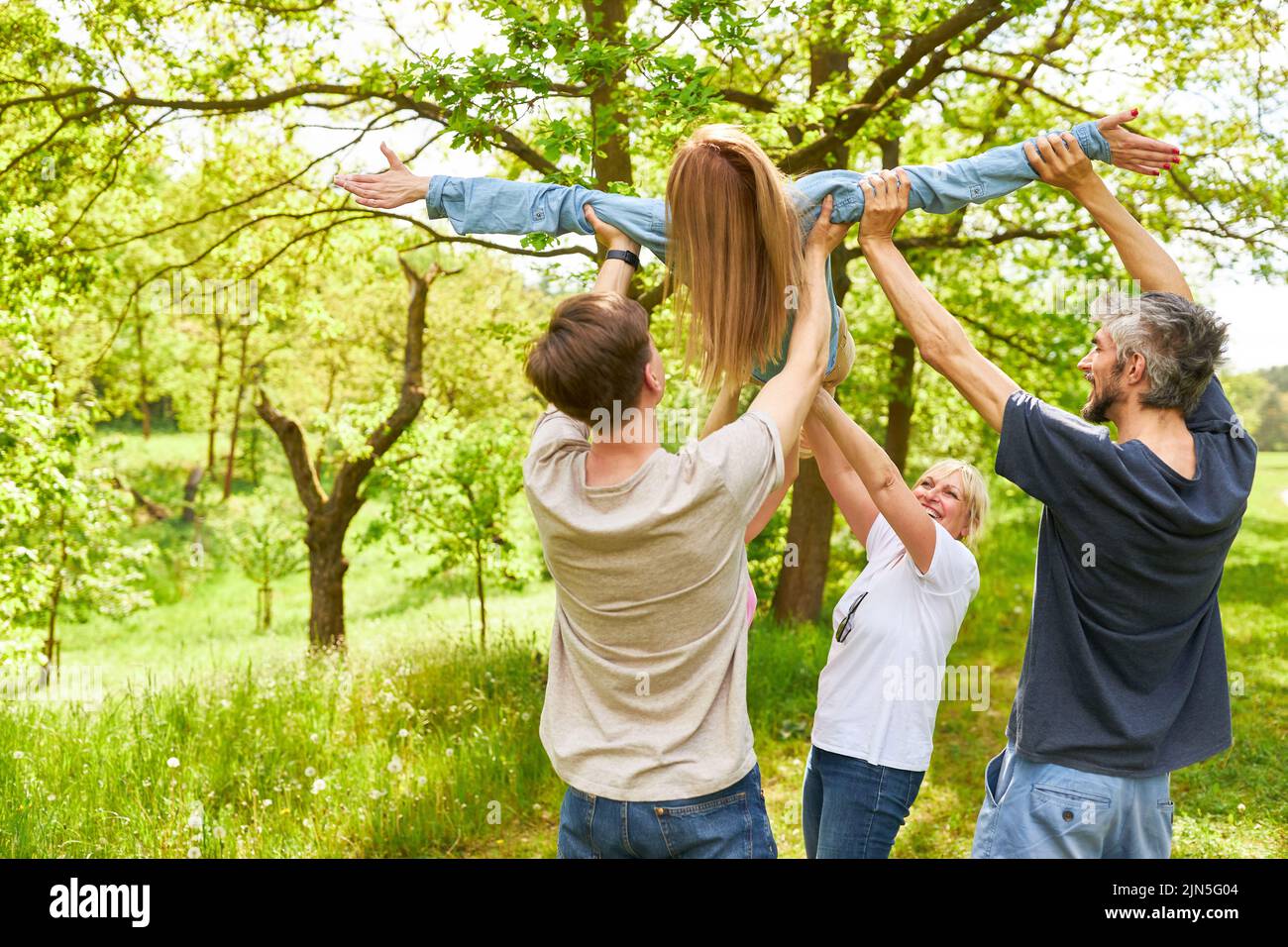 Young people lifting a woman in the air together at outdoor workshop ...