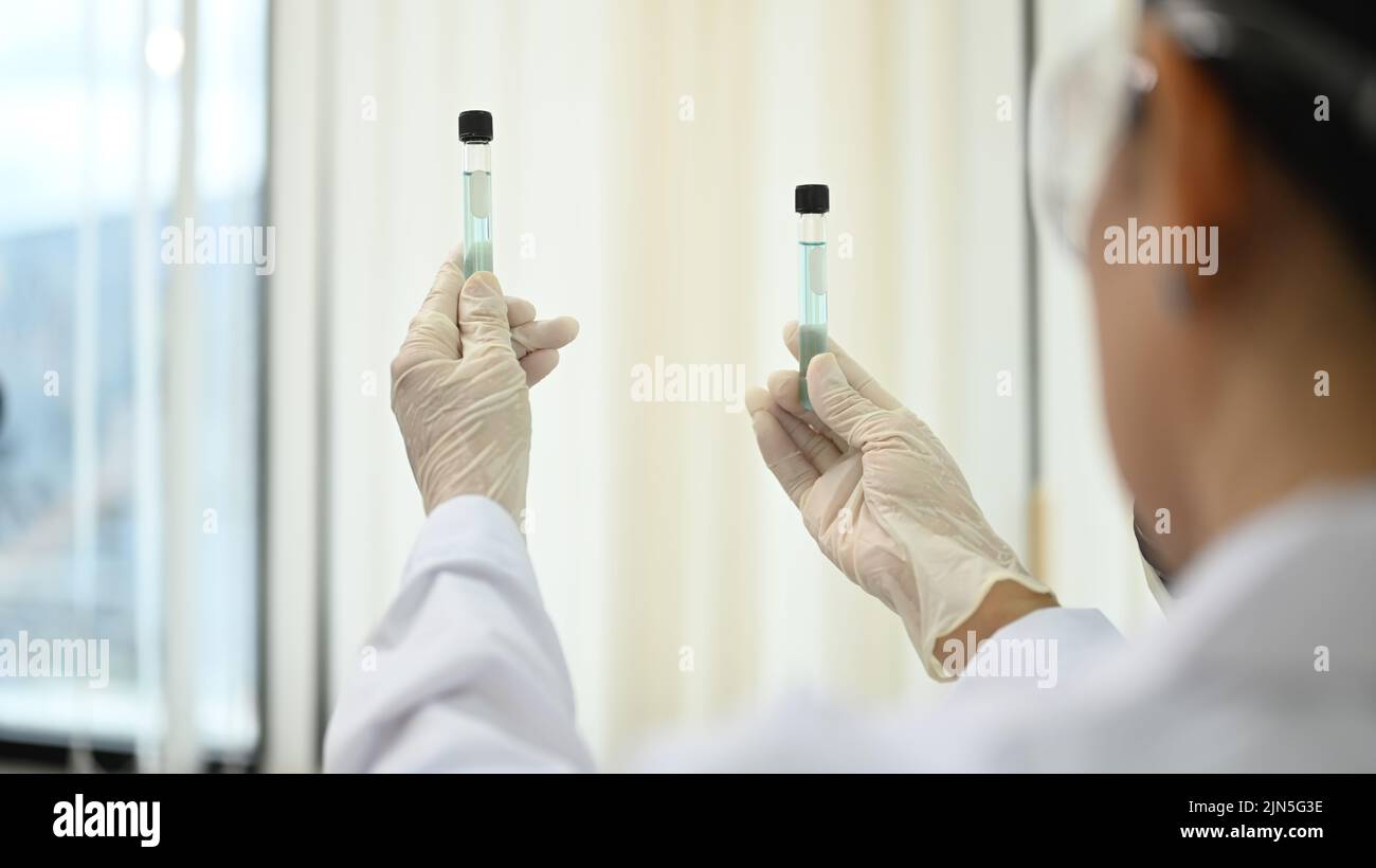 Over shoulder view of professional chemist holding test tube while ...