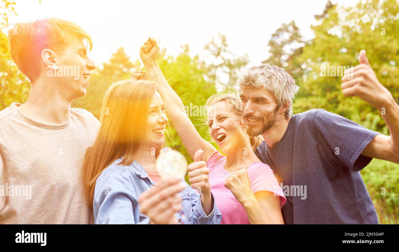 Happy people in team cheer as winner with medal in hand Stock Photo - Alamy