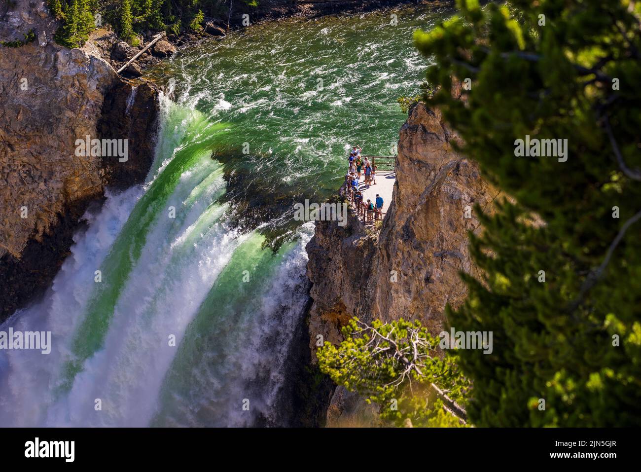 Visitors observe the Yellowstone River flow over the brink of Lower ...