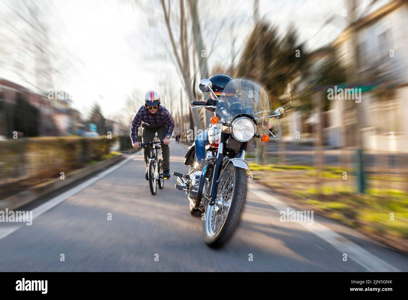 young adults simulate a mock race between motorcycle and bicycle Stock ...