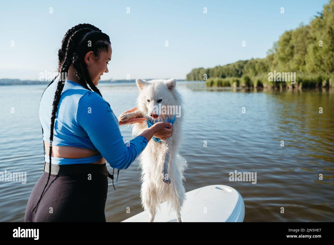 Young Woman with Locs Holding Her Pet Japanese Spitz on the Lake, Dog ...