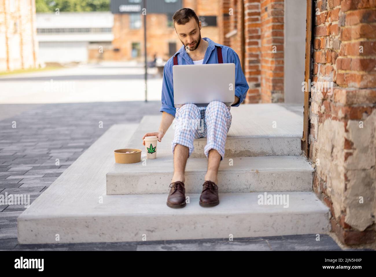 Stylish guy works on laptop computer on a street Stock Photo - Alamy