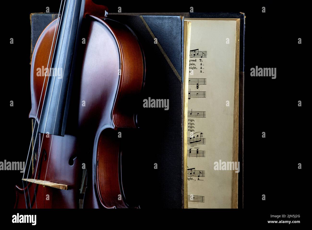 Upright violin against an old music book on a black background Stock ...