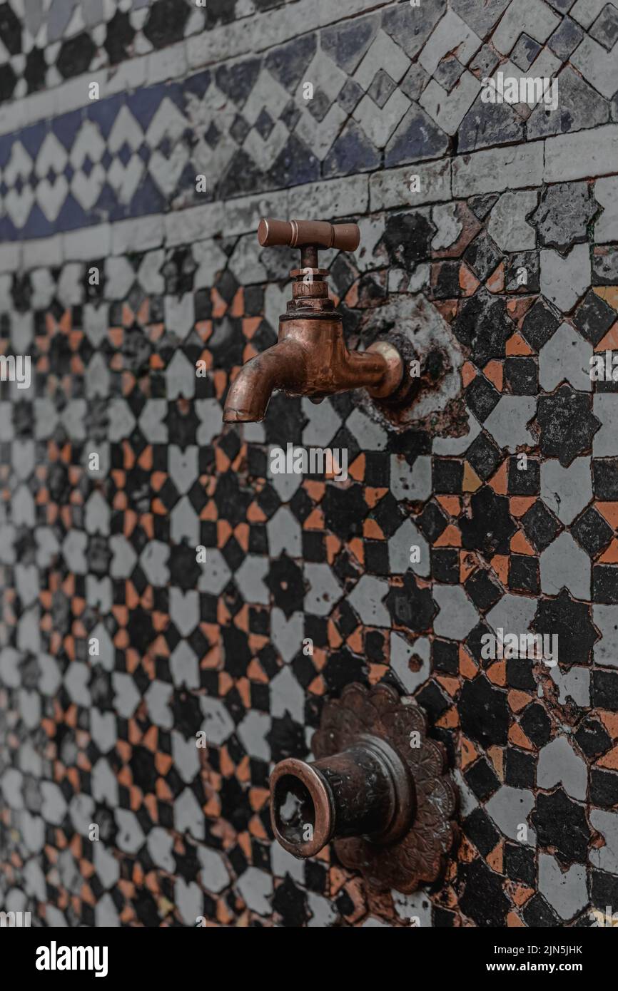 Traditional Moroccan mosaic fountain with a copper tap in the middle of ...