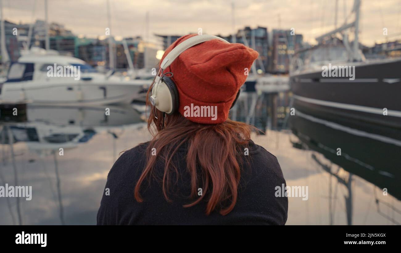 A shallow focus of a young girl with a red beanie listening to music ...