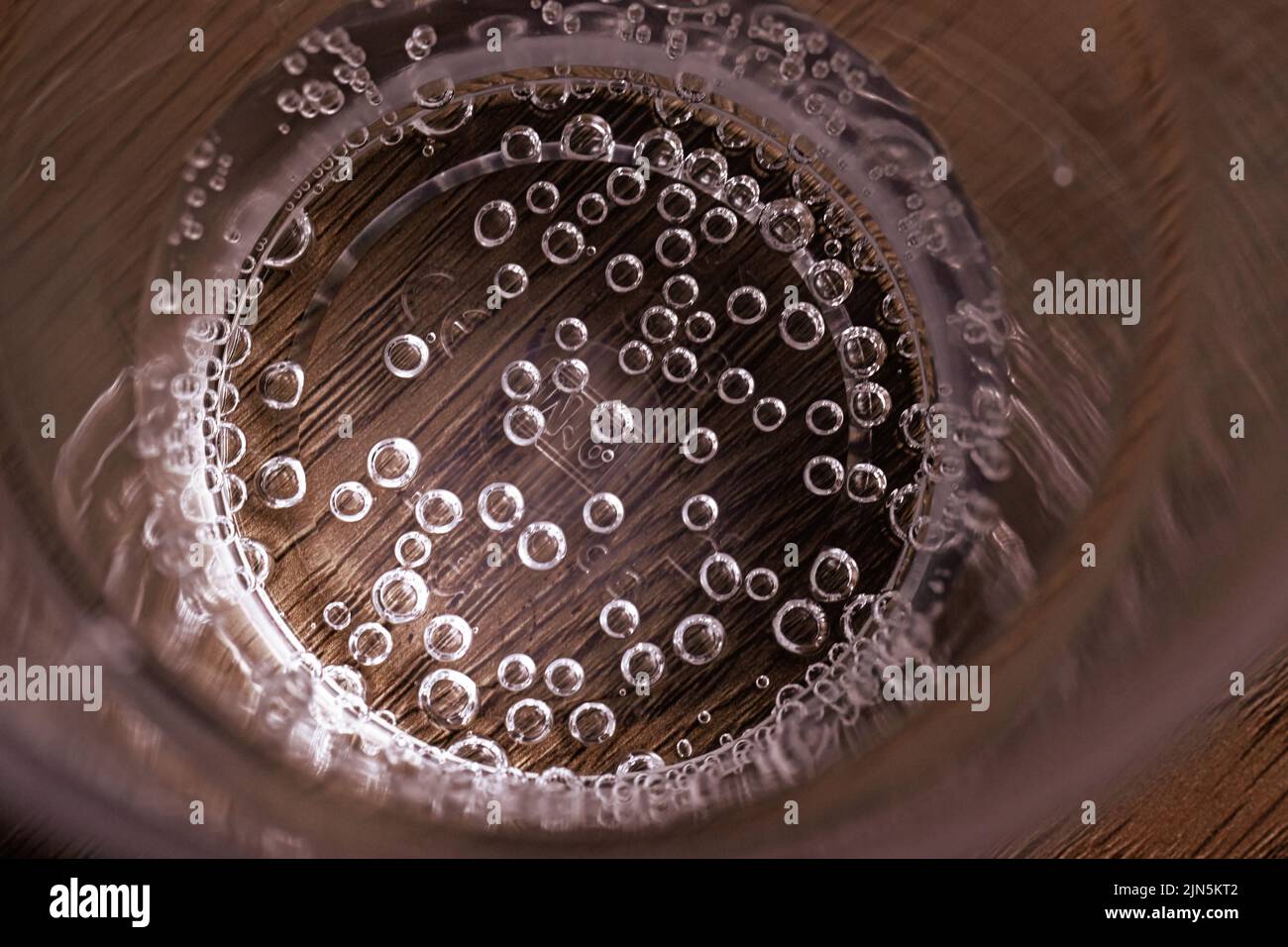 The bubbles of the sparkling water on the bottom of the see-thru ...