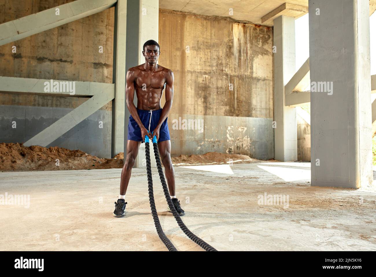 Rope workout. Sport man doing battle ropes exercise outdoor. Black male ...