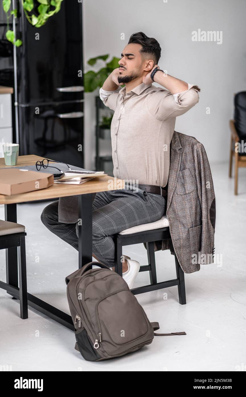 Man with closed eyes stretching sitting at table Stock Photo - Alamy
