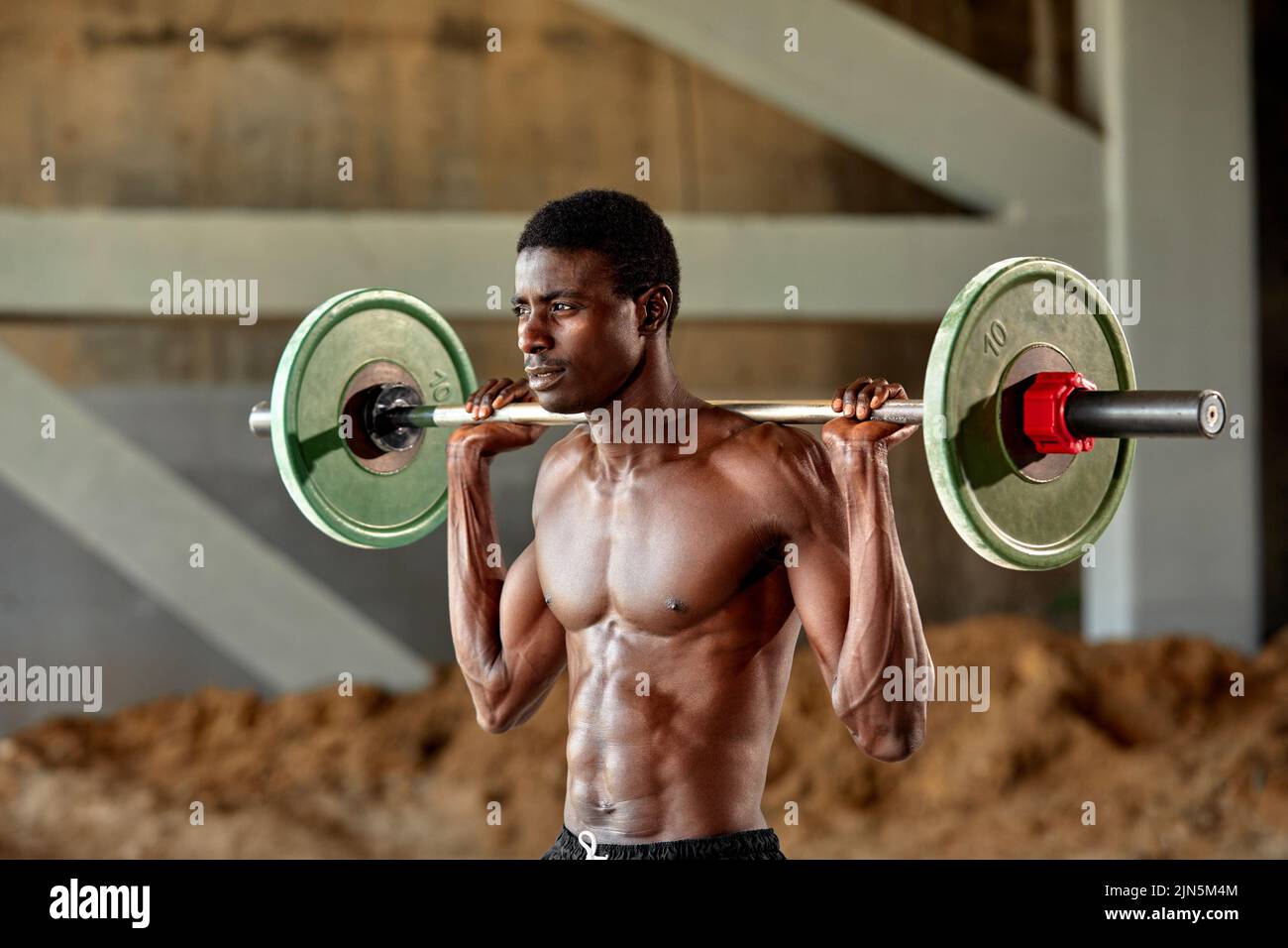 Athletic black young man lifting a heavy-weight barbell in outdoor gym ...