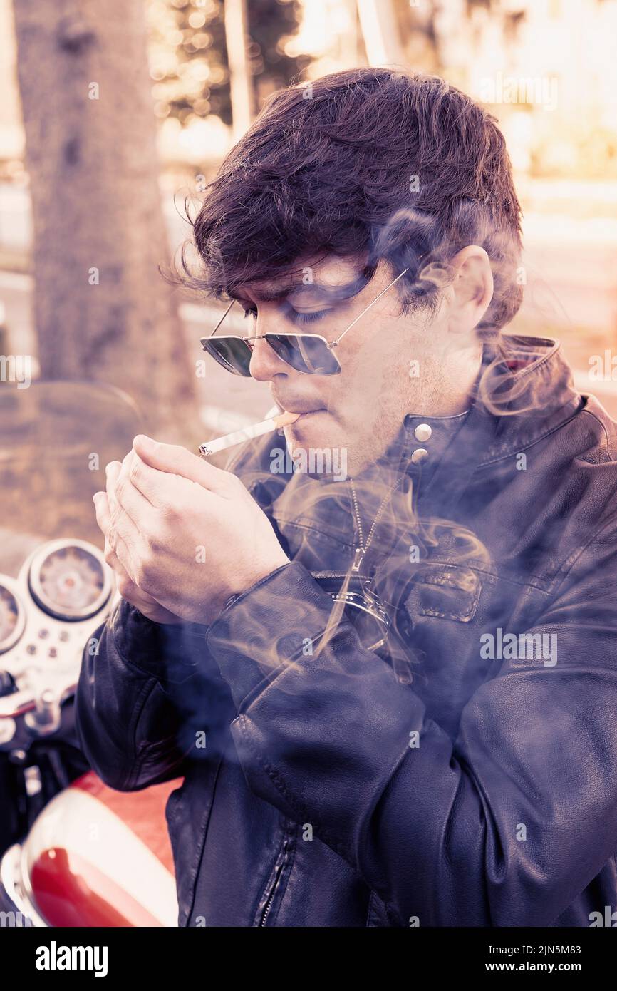 young biker relaxing smoking a cigarette Stock Photo - Alamy