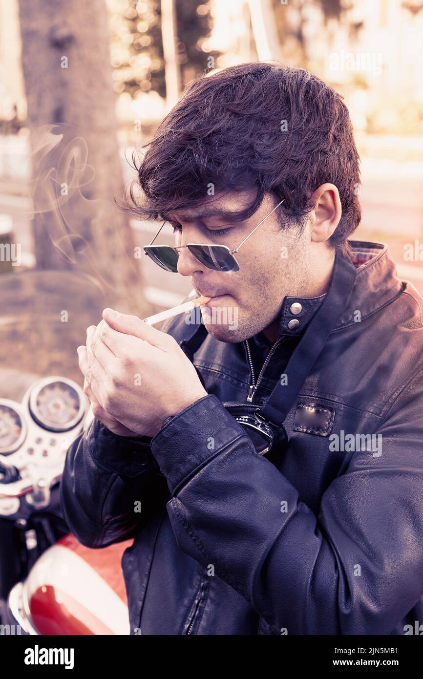 young biker relaxing smoking a cigarette Stock Photo - Alamy