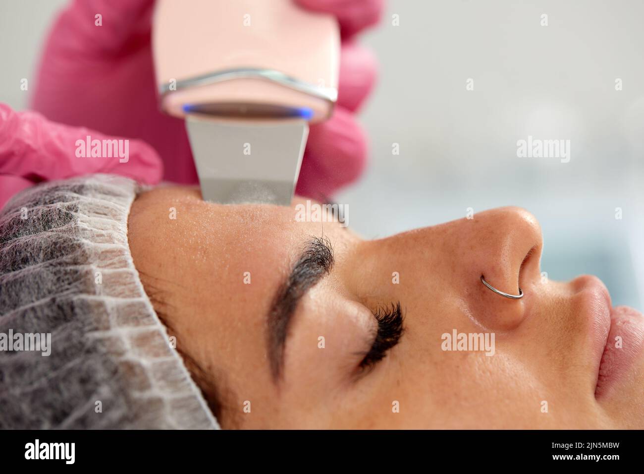 Beauty doctor with ultrasonic scraber doing procedure of ultrasonic ...