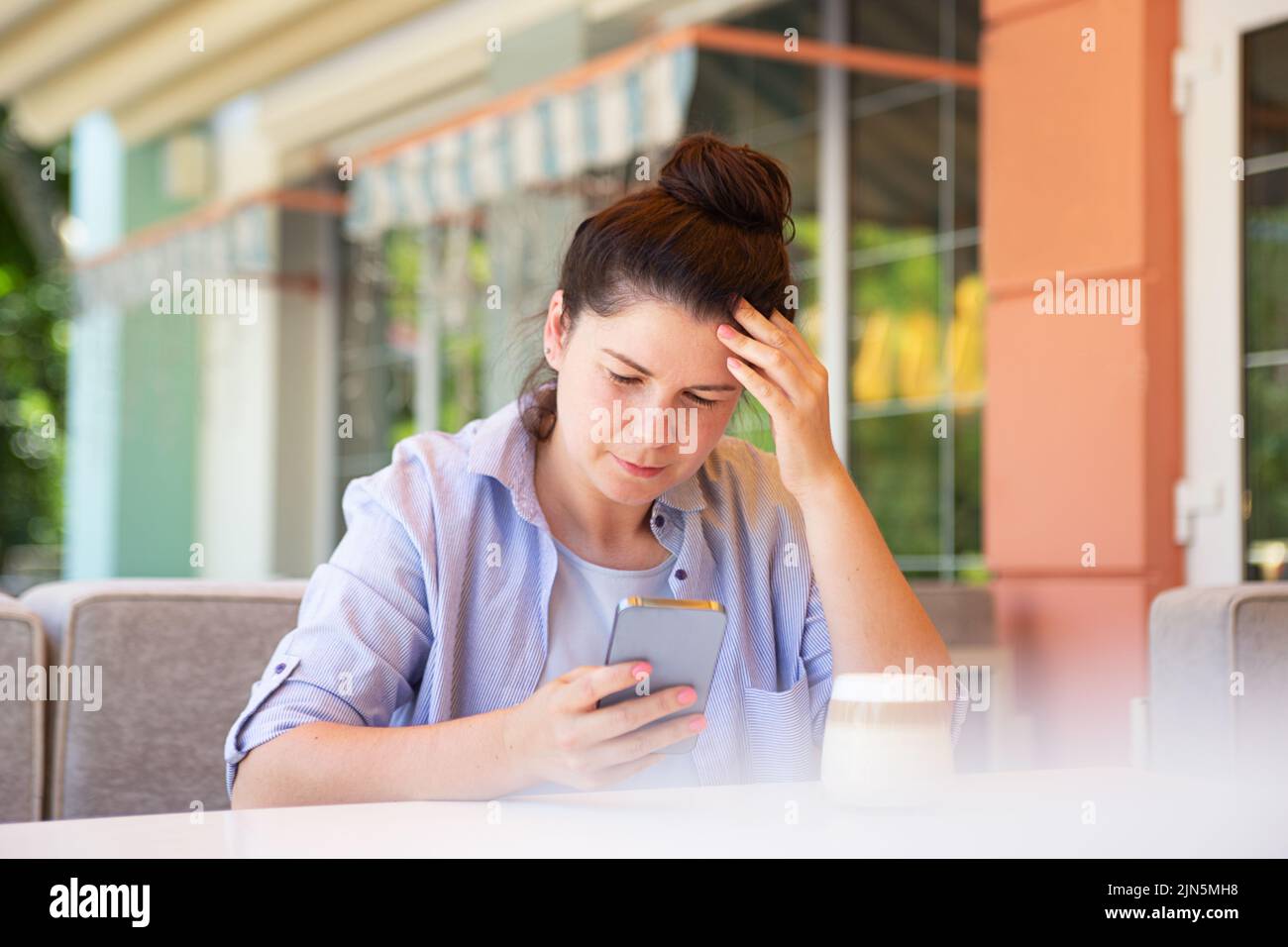 Tired bussines woman sitting outside with her mobile phone and sign ...