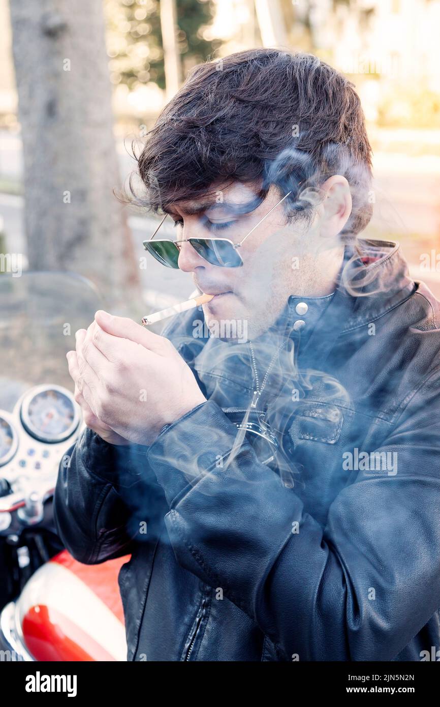young biker relaxing smoking a cigarette Stock Photo - Alamy
