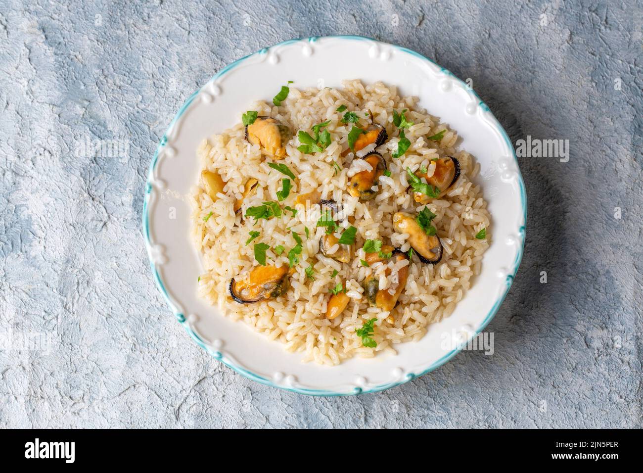 Mussel rice pilaf. Rice with mussels on small white plate on ceramic ...