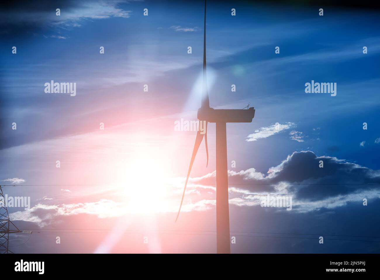 Wind turbine on the sunset. Blue energy Stock Photo - Alamy