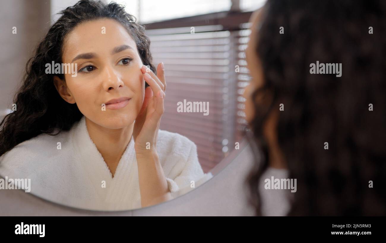 Young Attractive Woman In Bathrobe Looks In Mirror In Bathroom Touches