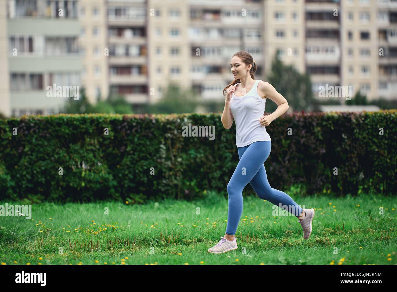 Woman in white t-shirt and leggings takes morning jog in residential ...