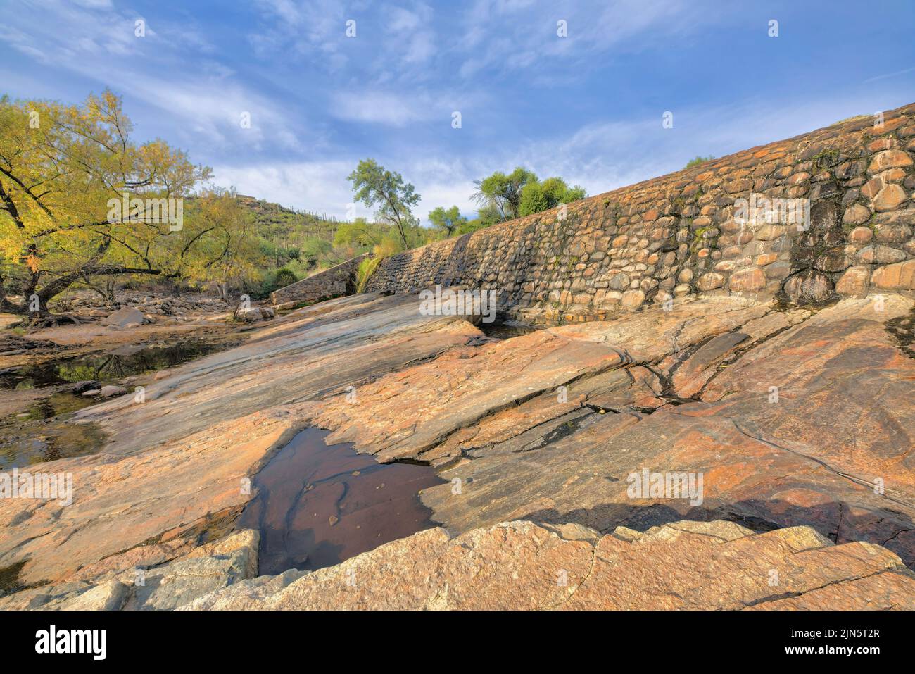 Stone wall and large rocks with puddle of water in between the cracks ...