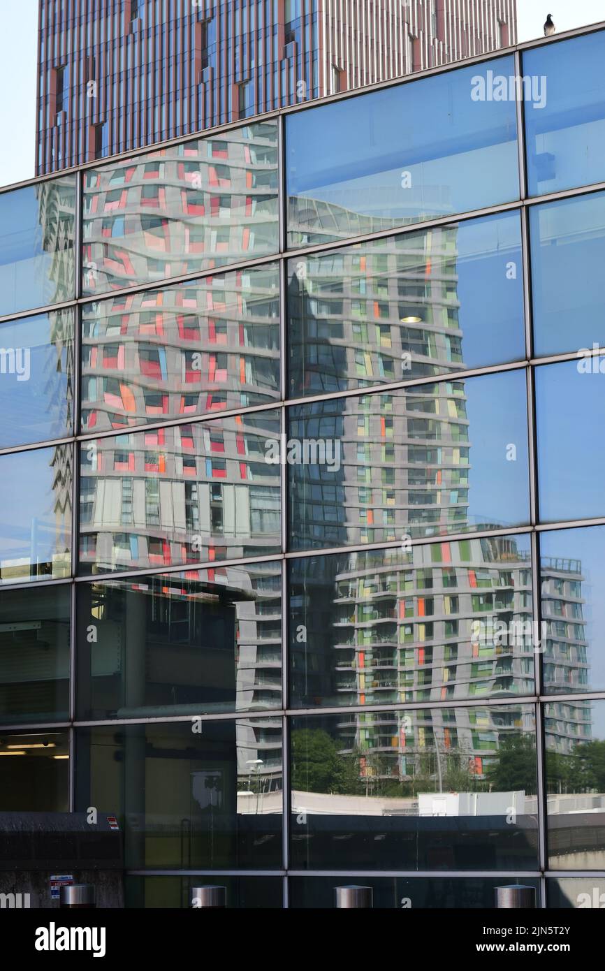 The reflection of the buildings on the glassy exterior of the structure ...