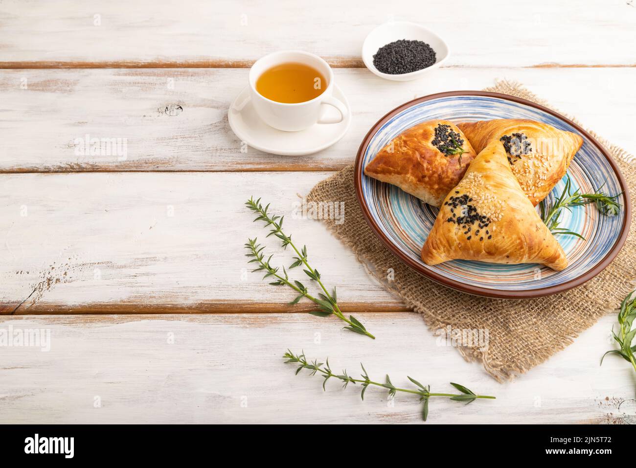 Homemade asian pastry samosa, cup of green tea on white wooden ...