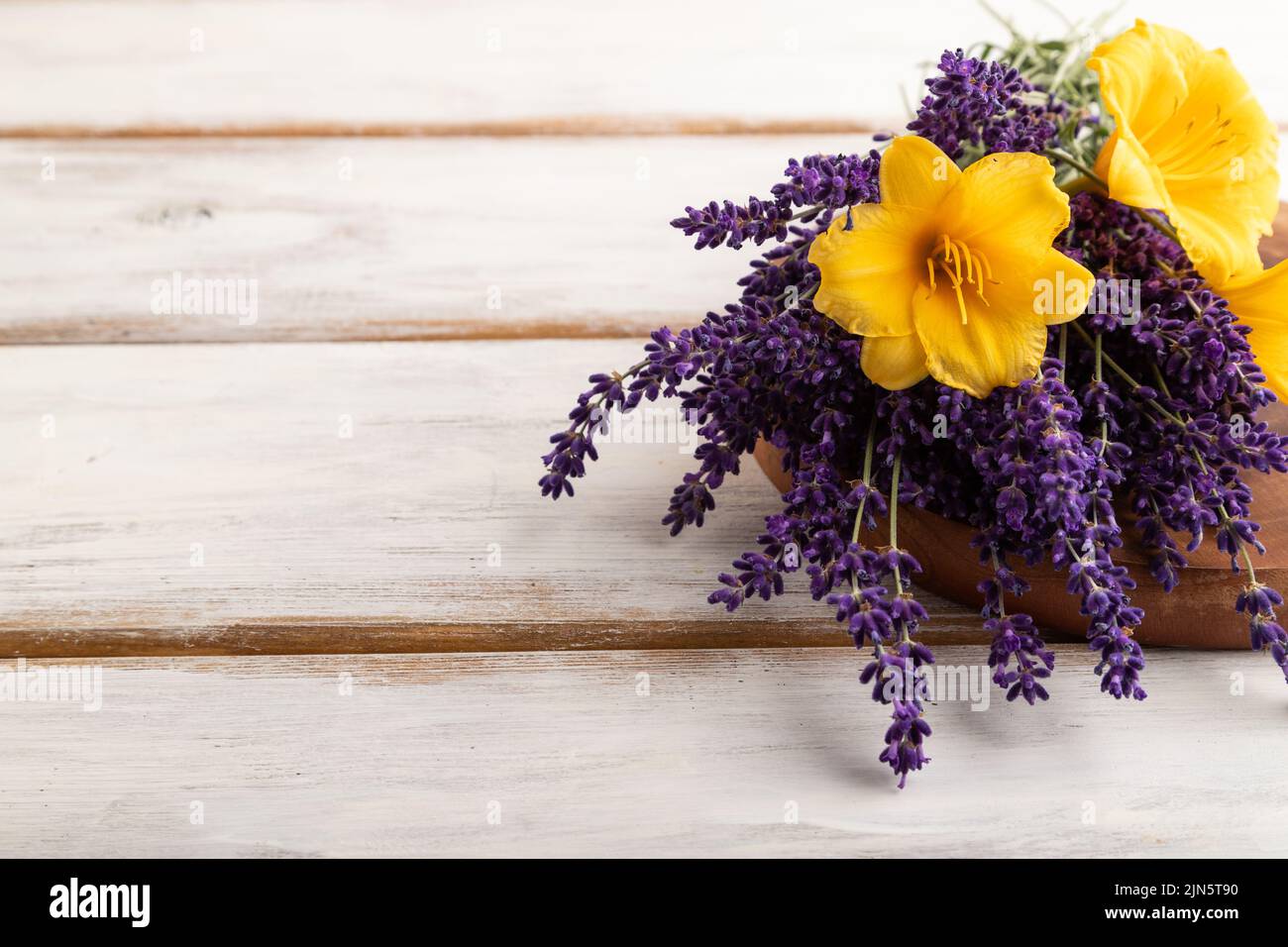 Beautiful day lily and lavender flowers on white wooden background ...