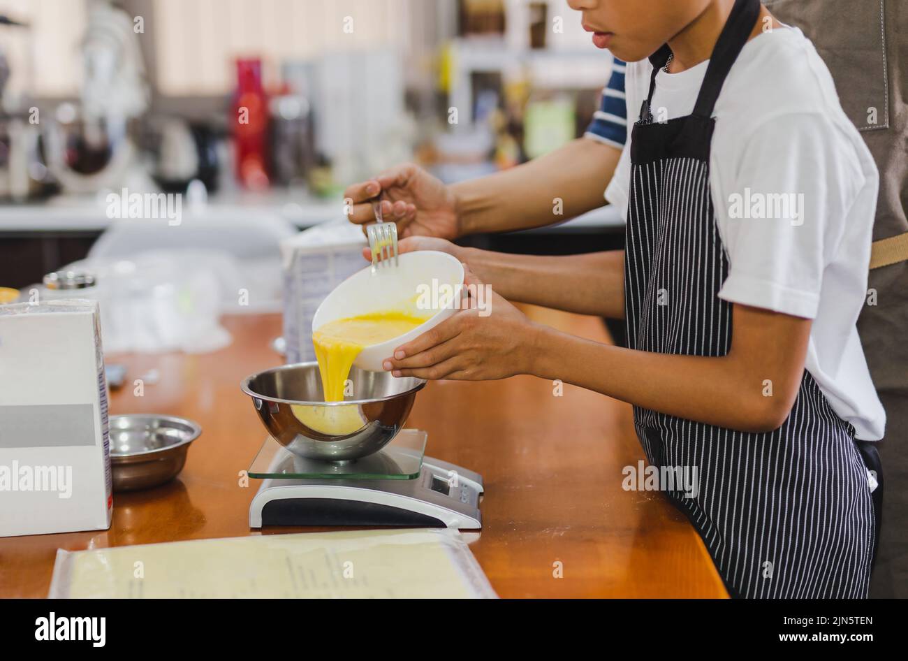 Boy helping mum pouring egg yolks into bowl for baking cake Stock Photo ...