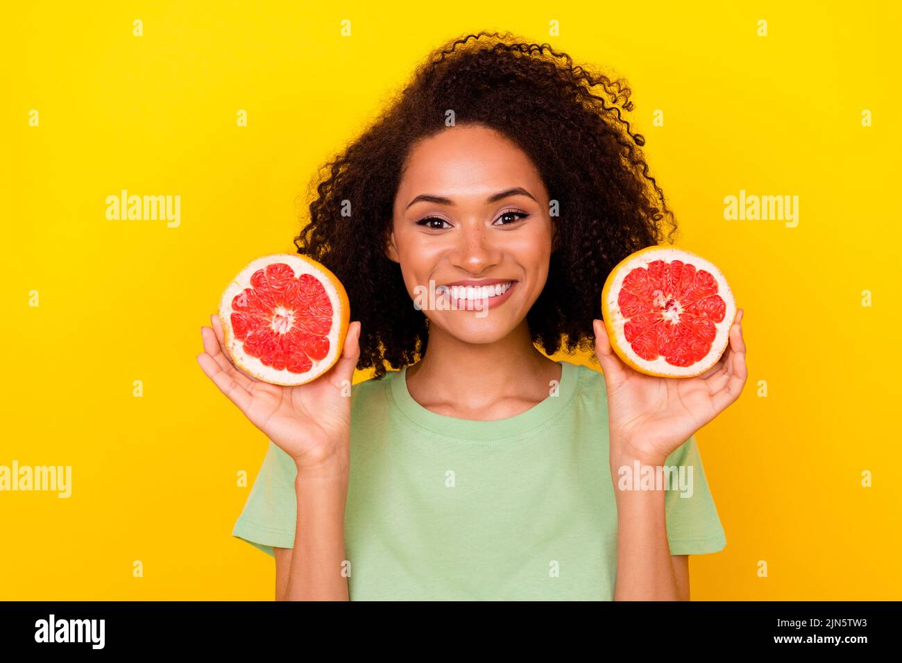 Photo of adorable cheerful lady wear green t-shirt rising two orange ...