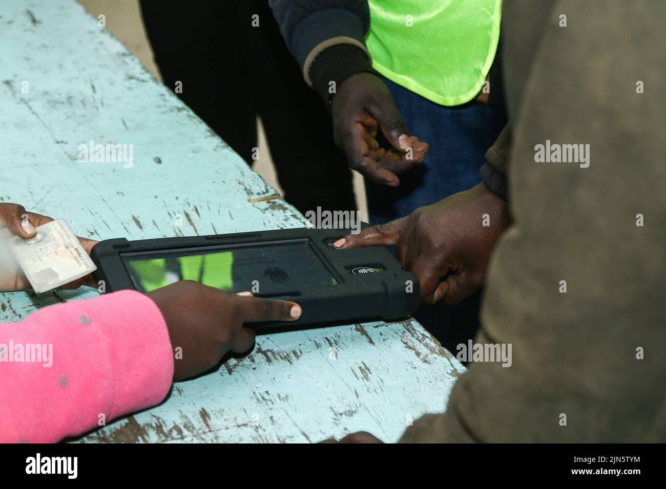 An election official confirms a voter's biometric details in a ...
