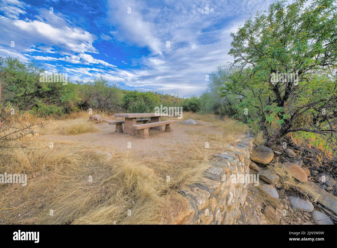 Concrete picnic table on a dirt ground with stone walls at Tucson ...