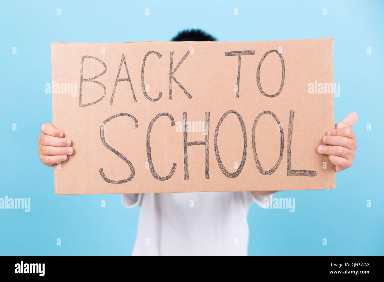an anonymous child displays a sign with the message: "back to school ...