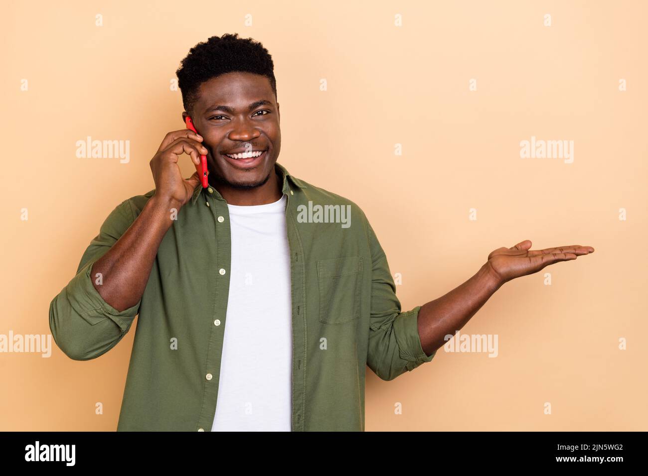 Photo of cute young brunet guy talk telephone hold promo wear casual ...