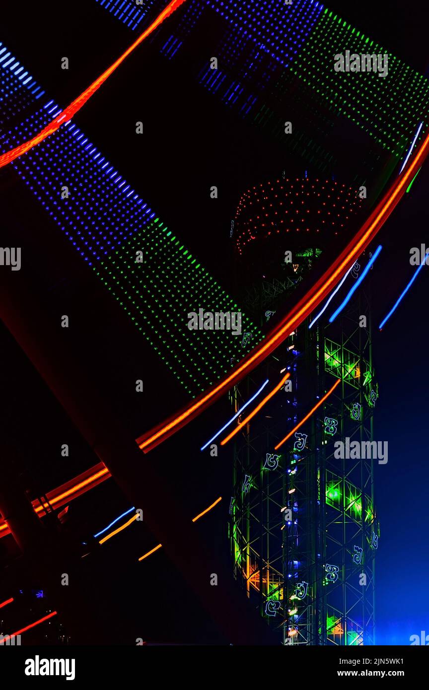 Night illumination of Alphabet tower seen through ferris wheel in ...