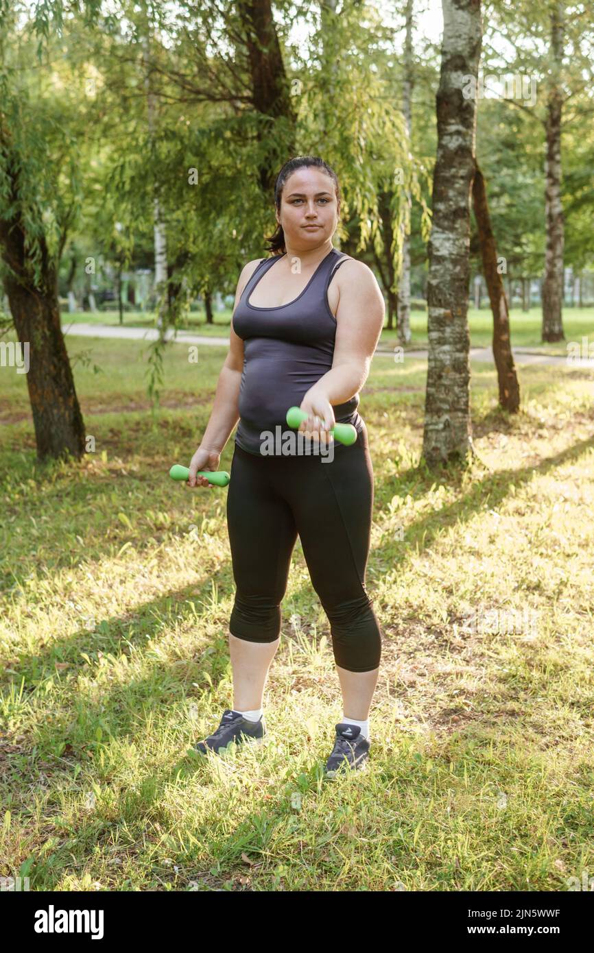 A charming brunette woman plus-size body positive practices sports in ...