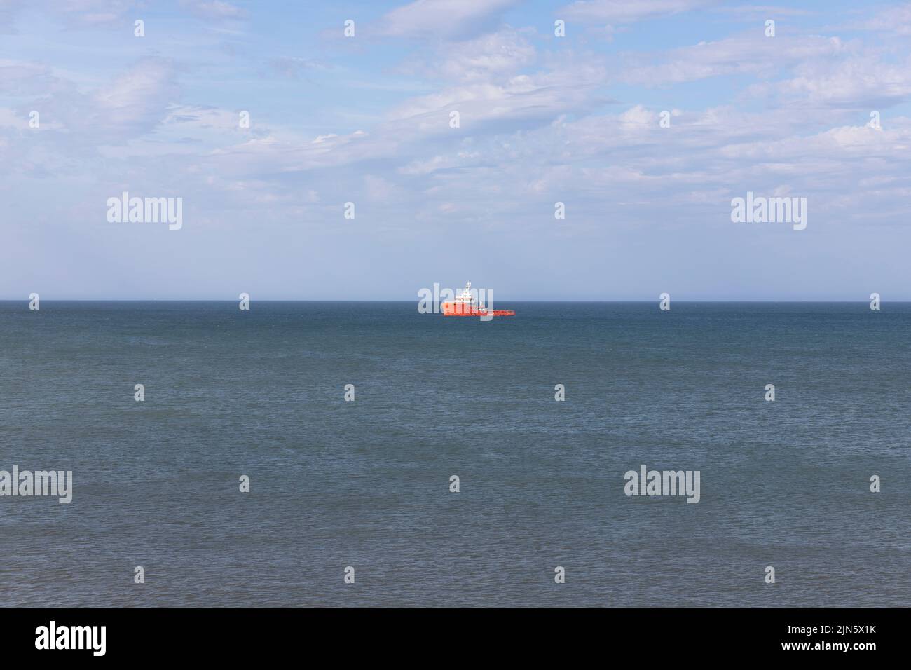 A single orange 'rescue' boat alone on the centre of the horizon, out ...