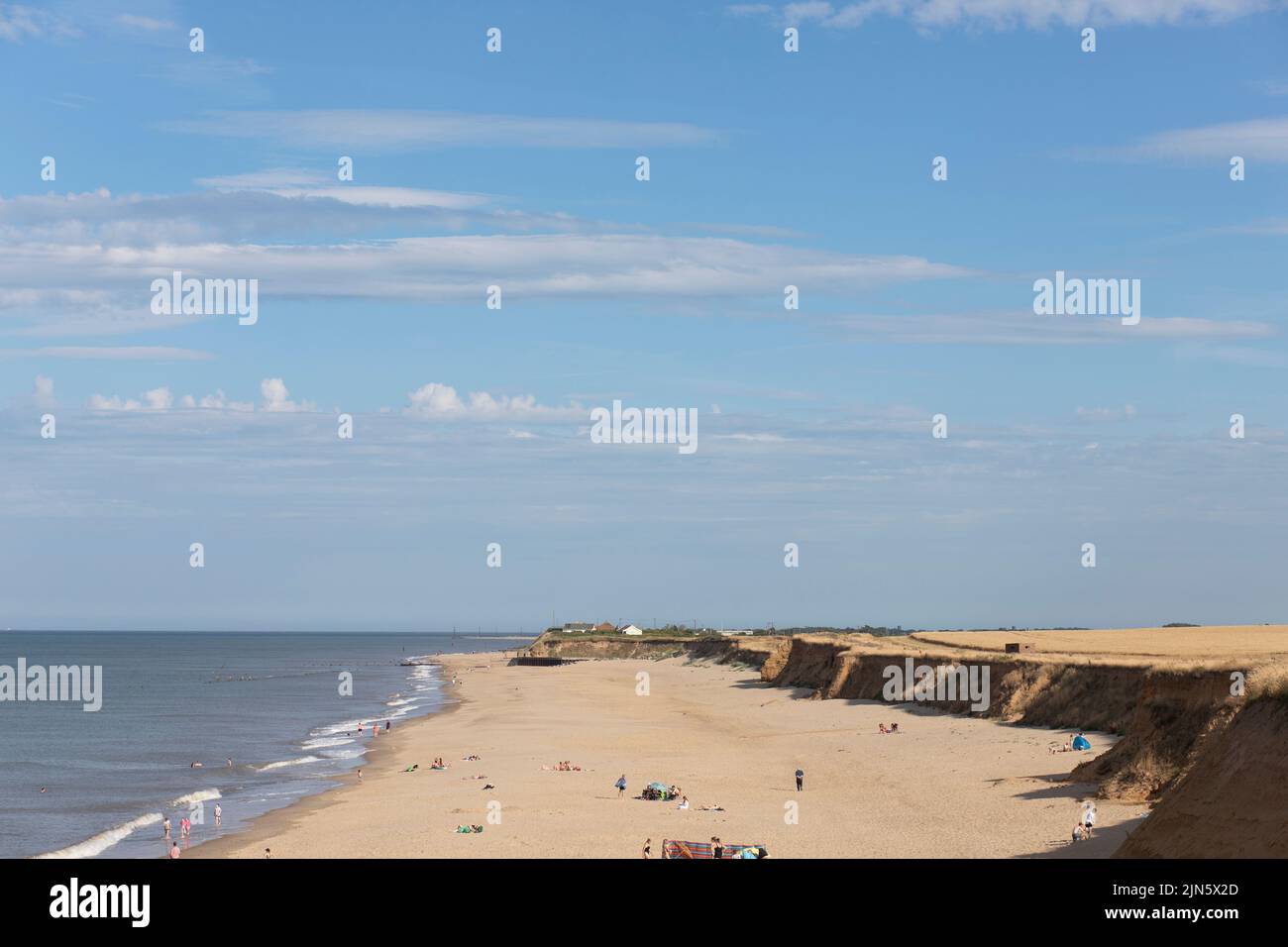 People on the beach at Happisburgh, Norfolk, with the cliffs (eroding ...