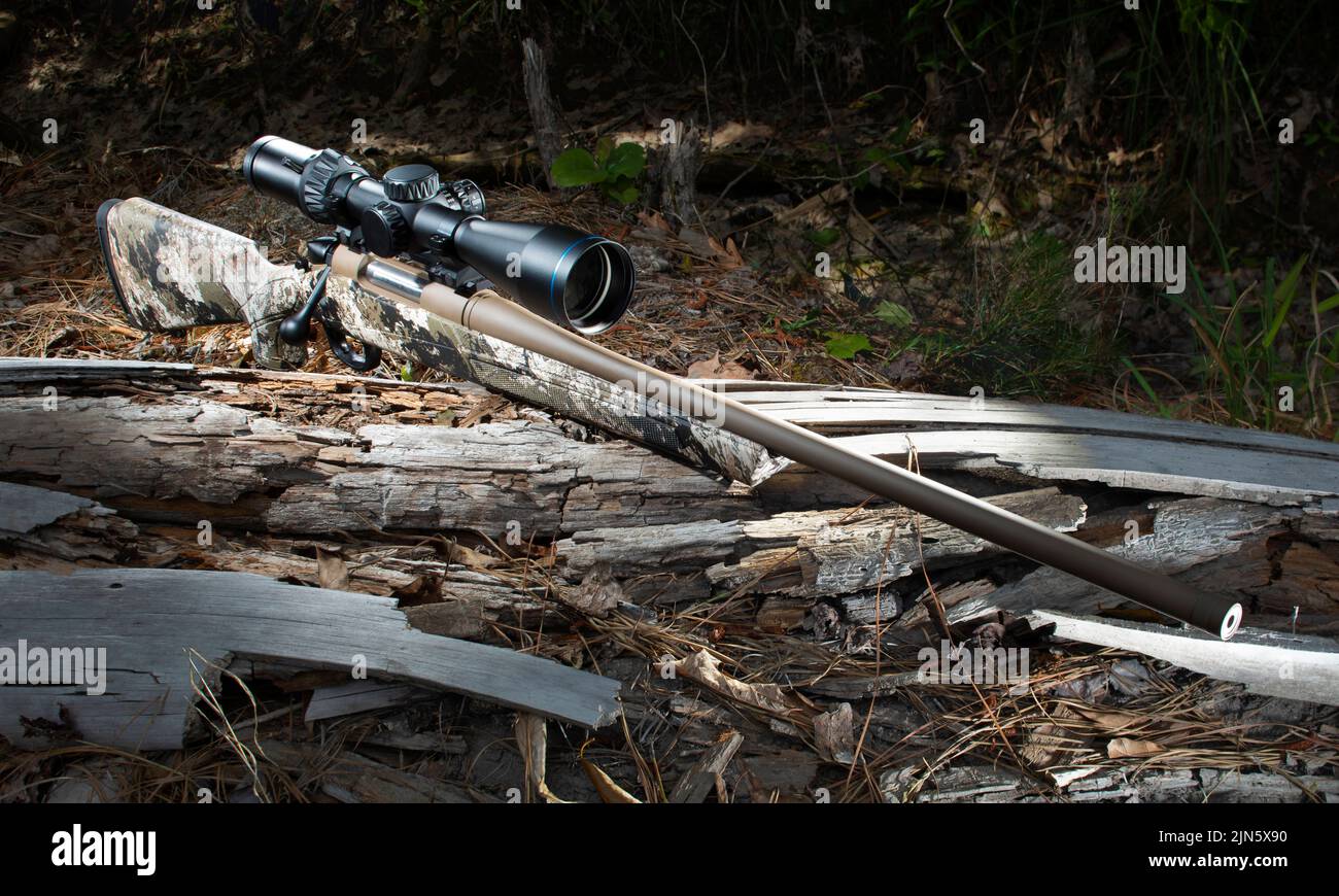 Bolt action rifle and high powered scope across a rotting log in the ...