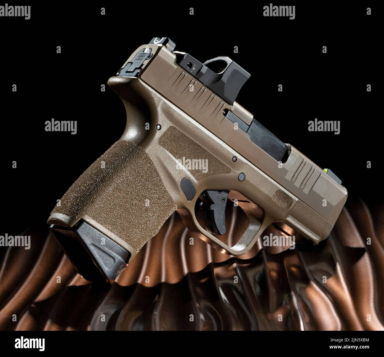 Modern polymer semi automatic pistol with red dot sight on a brown wavy ...