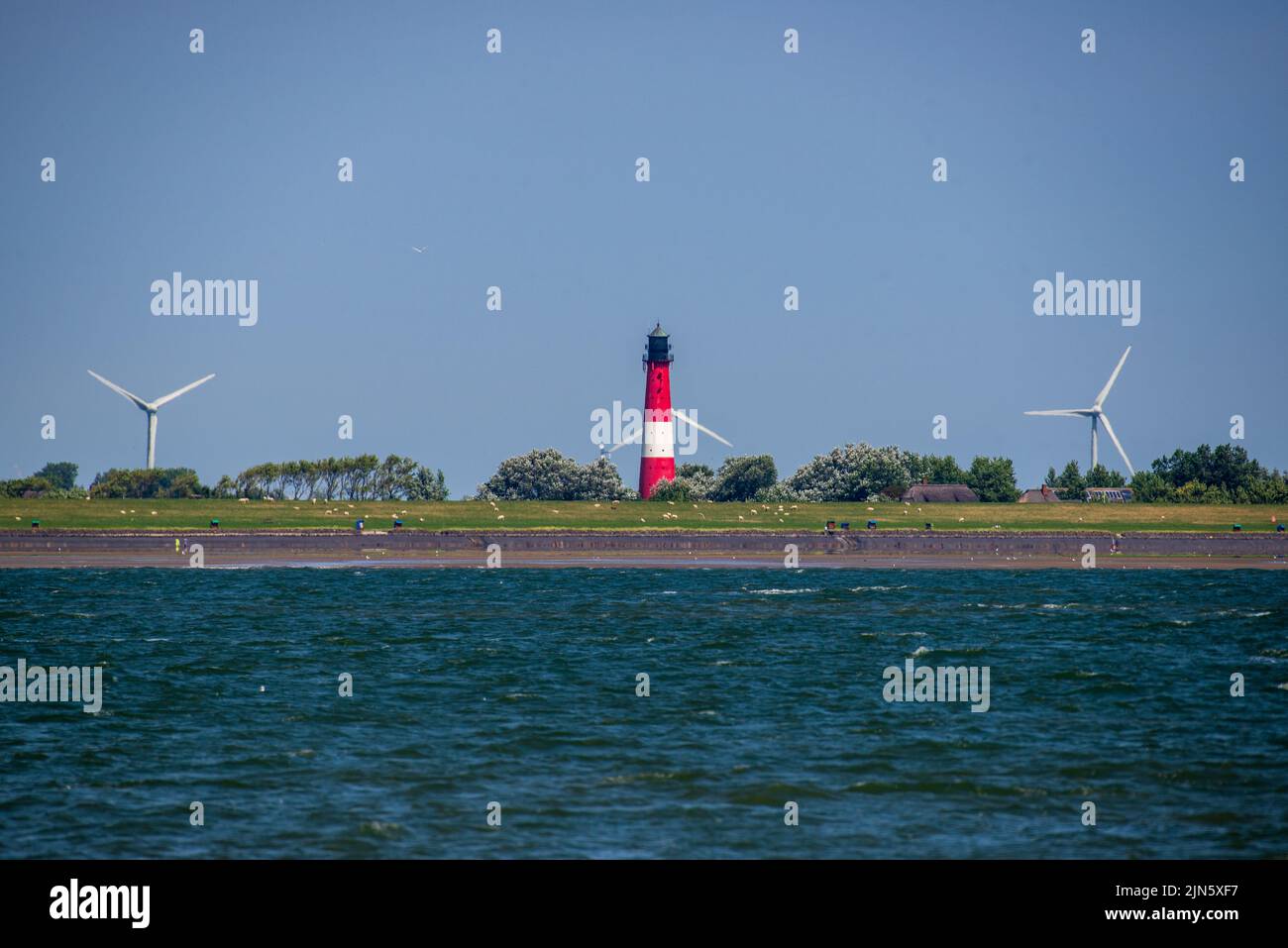 View of a lighthouse with wind turbines in the background Stock Photo ...