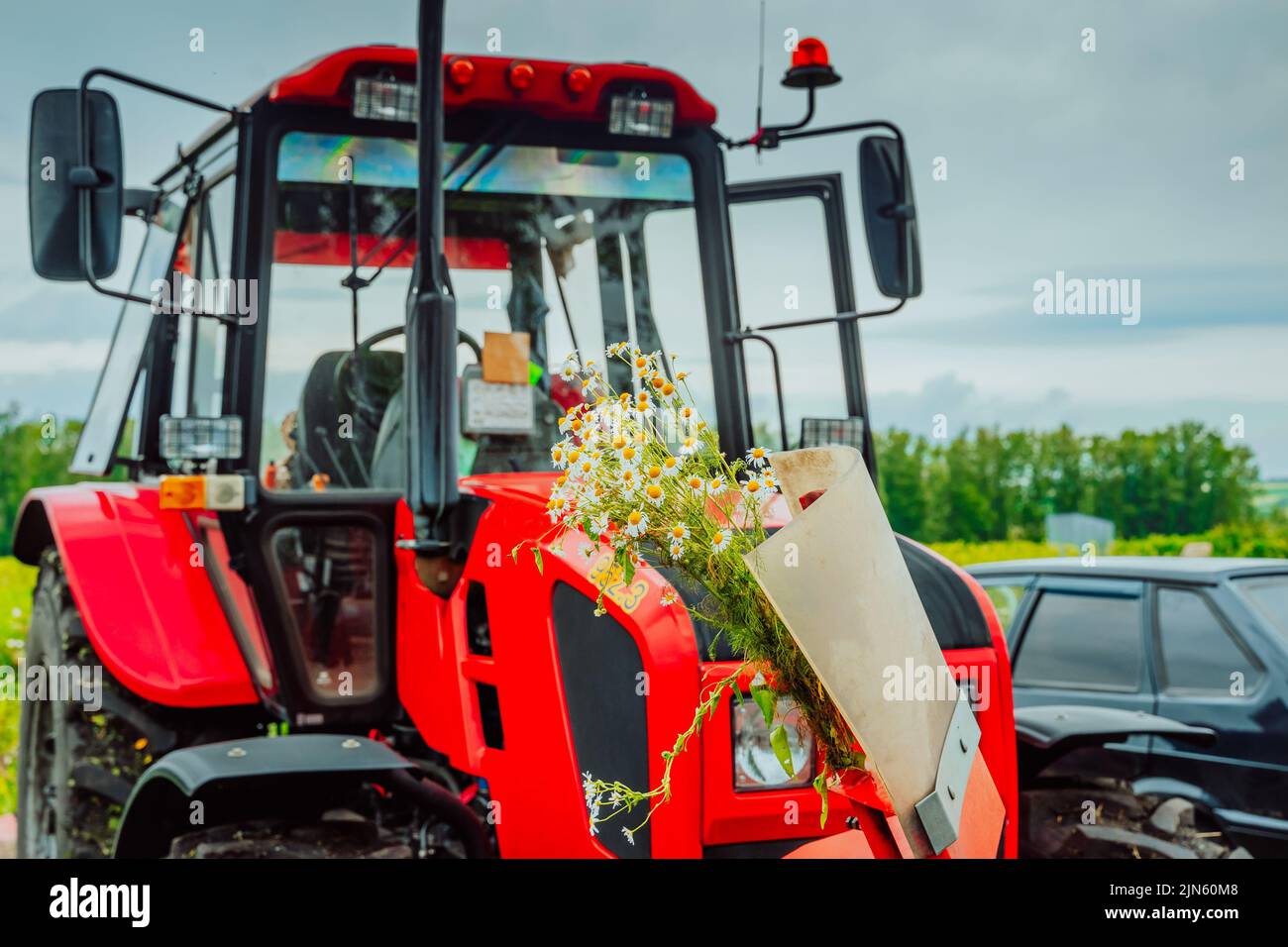 Red tractor in a rural landscape. Harvesting in the field. The tractor ...
