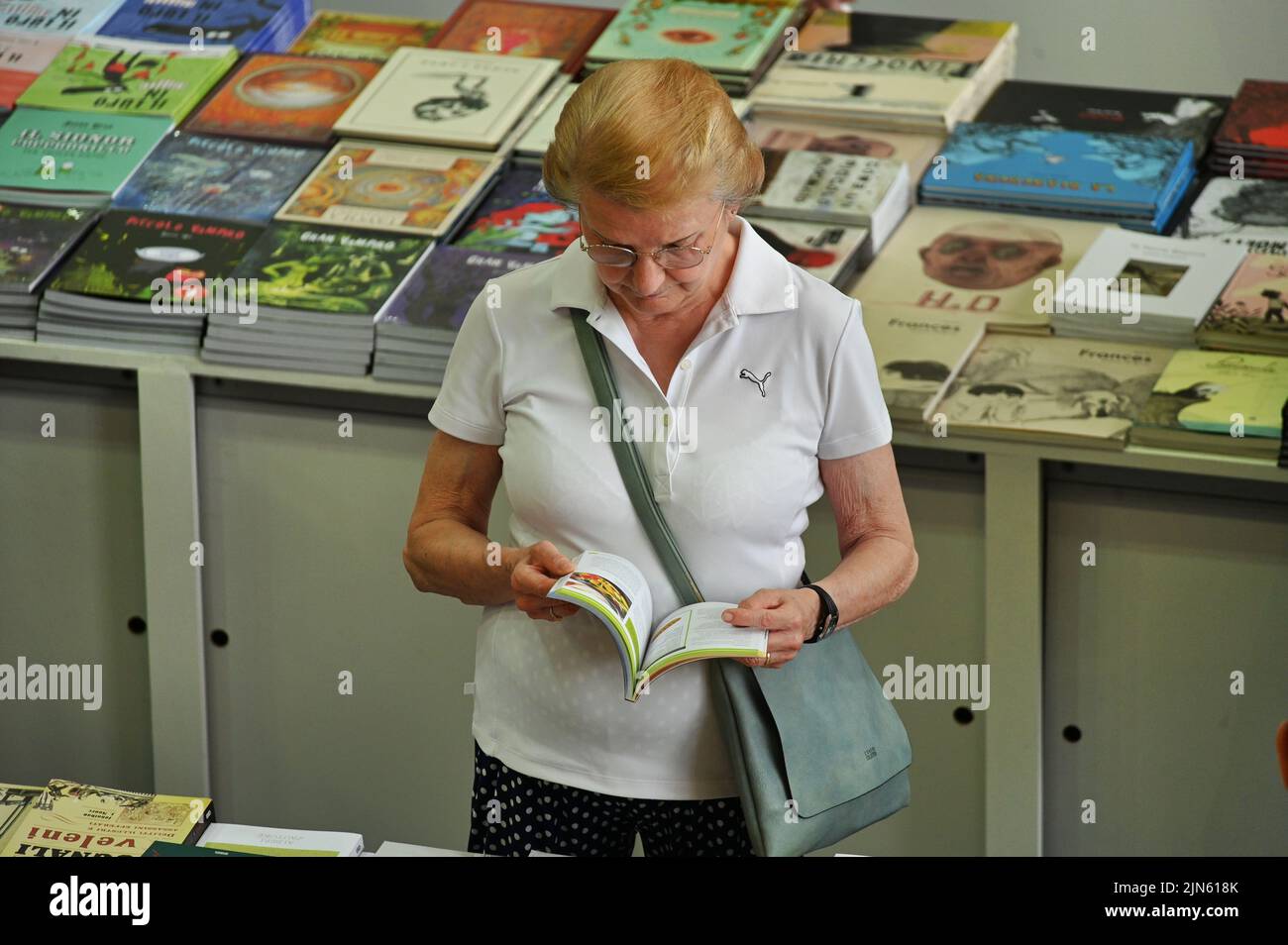 A vertical shot of an aged woman reading a book at culture festival ...