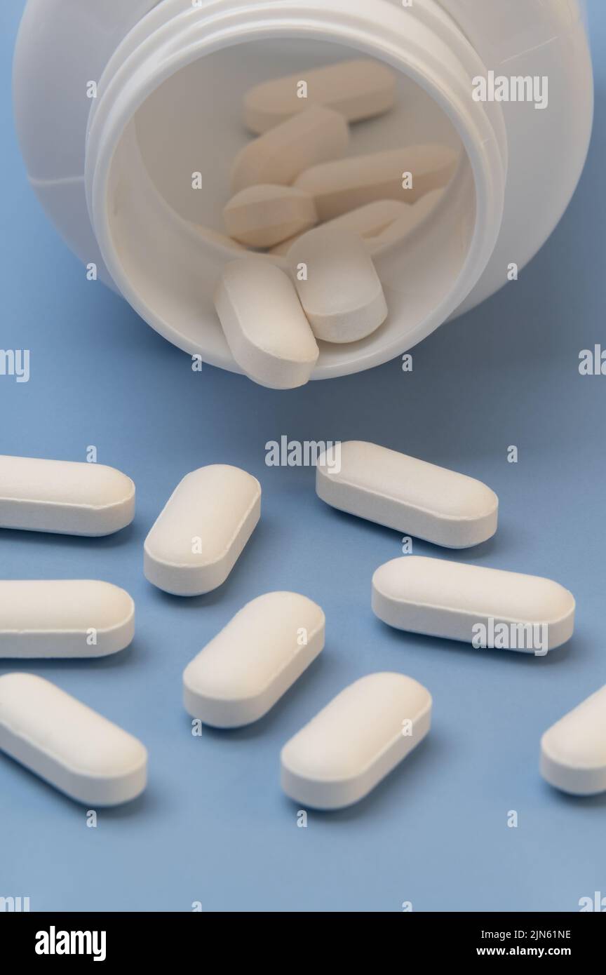 Vitamins tablets supplements Medicine coming out of bottle on Blue ...