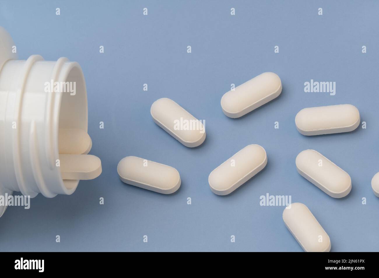 Vitamins tablets supplements Medication coming out of bottle on Blue ...