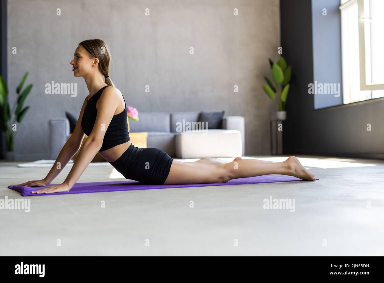 Young woman practicing yoga and lying in Cobra pose on a fitness mat at ...