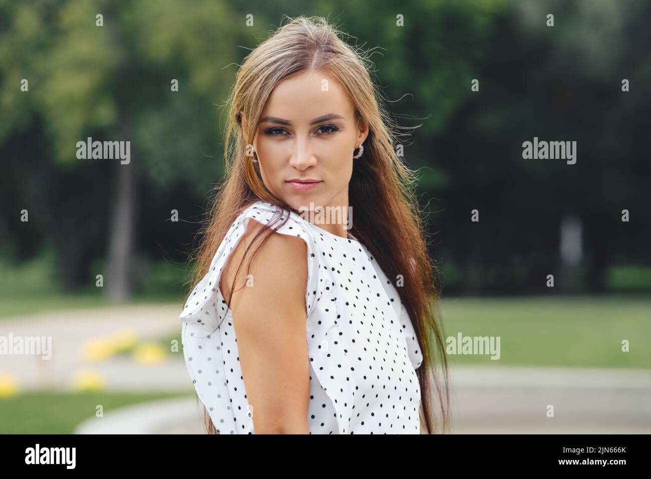Pretty young woman with long hair looks suspicious over the shoulder ...