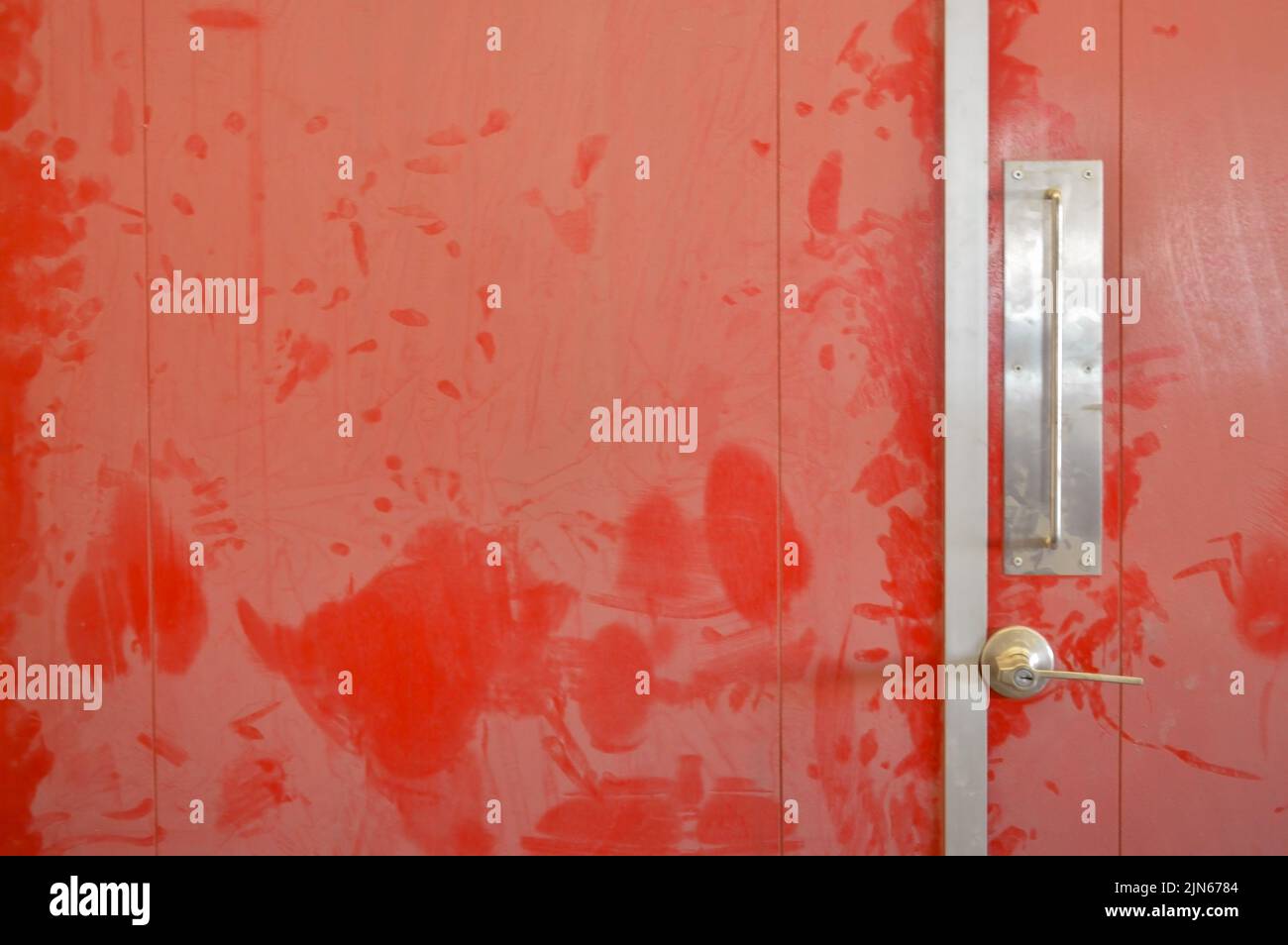 An old, dusty red wooden door with stains all over it in a factory ...