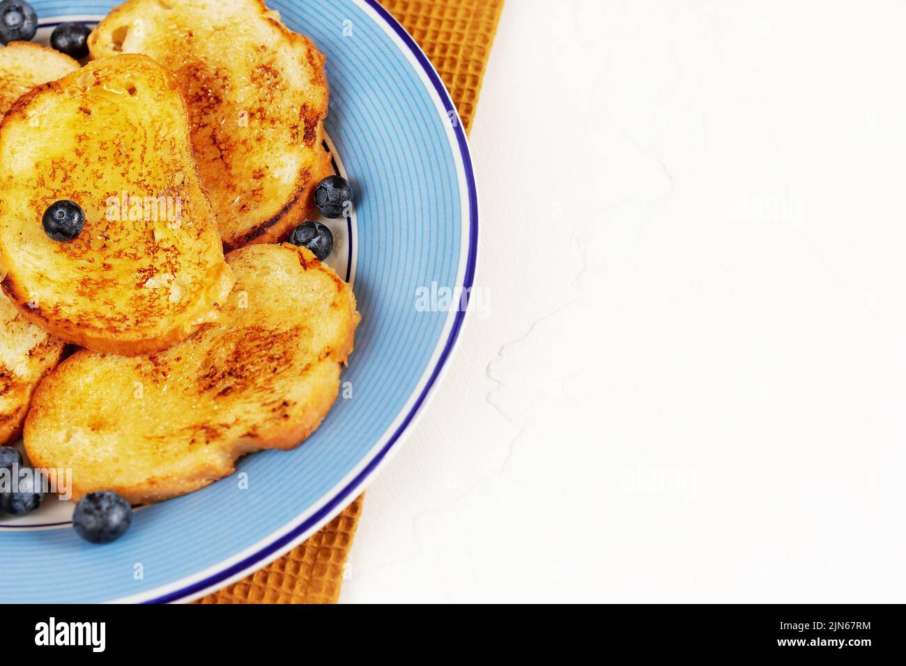 French toasts with honey and blueberry on a blue plate on a white ...