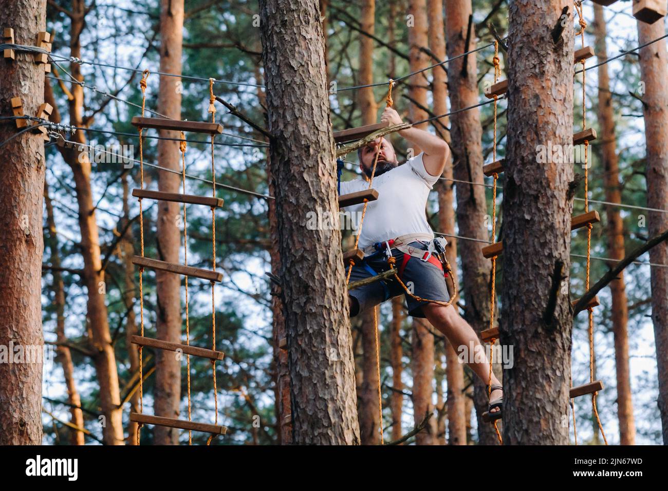 A man overcomes an obstacle in a rope town. A man in a forest rope park ...